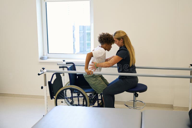 Female Physiotherapist Helps Young Patient Practice Standing Up from ...