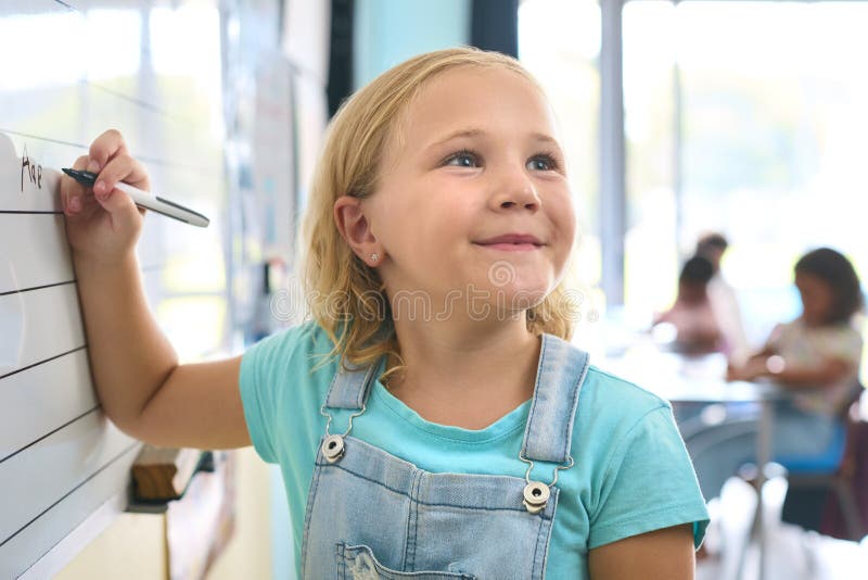 Female Primary or Elementary School Student Writing on Whiteboard in ...