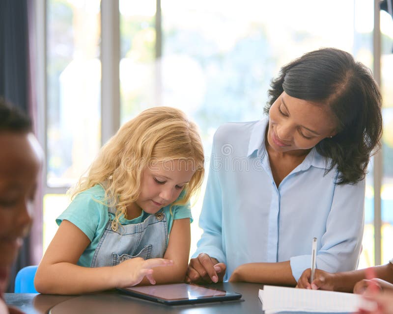 Female Primary or Elementary School Teacher in Multi-Cultural Class with Map in Geography Lesson ...