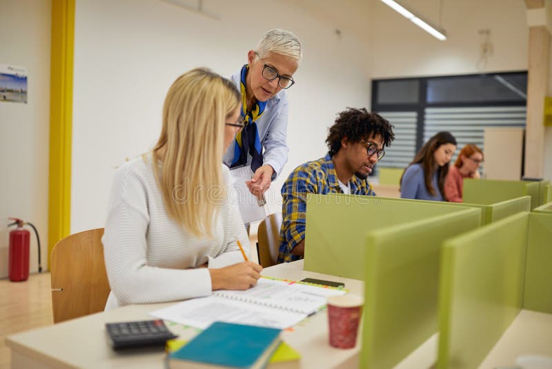 Female Professor Correcting Students Work Stock Photo - Image of ...