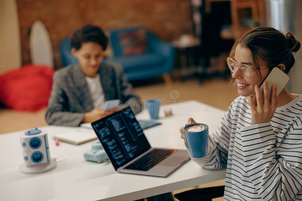 Female Programmer is Talking Phone while Working on Laptop and Drinking ...