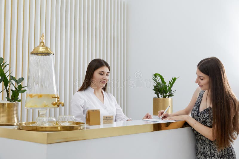 Female Receptionist at Reception Desk with a Client in a Modern Office ...
