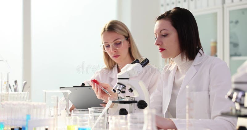Female Researchers Conduct Microscopic Analysis of Sample in Lab Stock ...