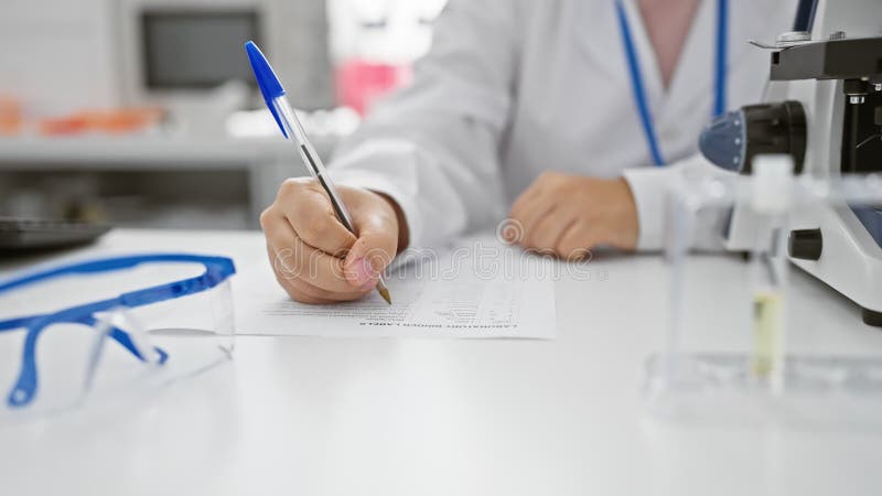 A Female Scientist Conducts Research in a Laboratory, Writing Notes ...