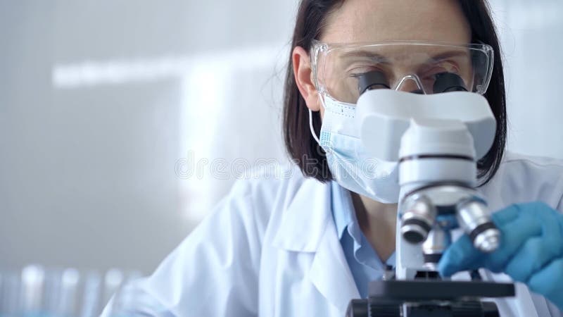 Female Scientist in Lab Goggles, Protective Mask and Gloves is Using ...