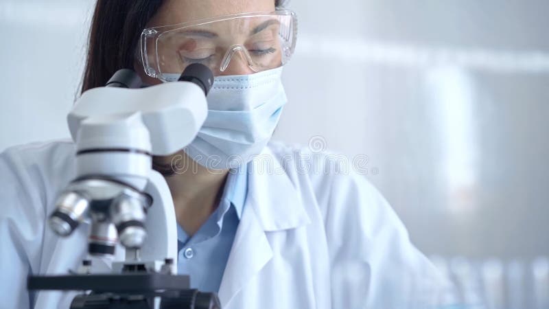 Female Scientist in Lab Goggles, Protective Mask and Gloves is Using ...