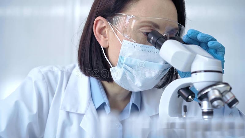 Female Scientist in Lab Goggles, Protective Mask and Gloves is Using ...