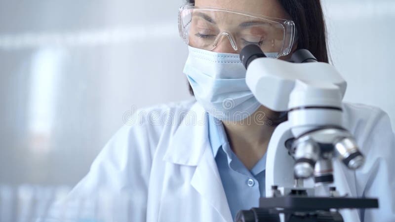 Female Scientist in Lab Goggles, Protective Mask and Gloves is Using ...