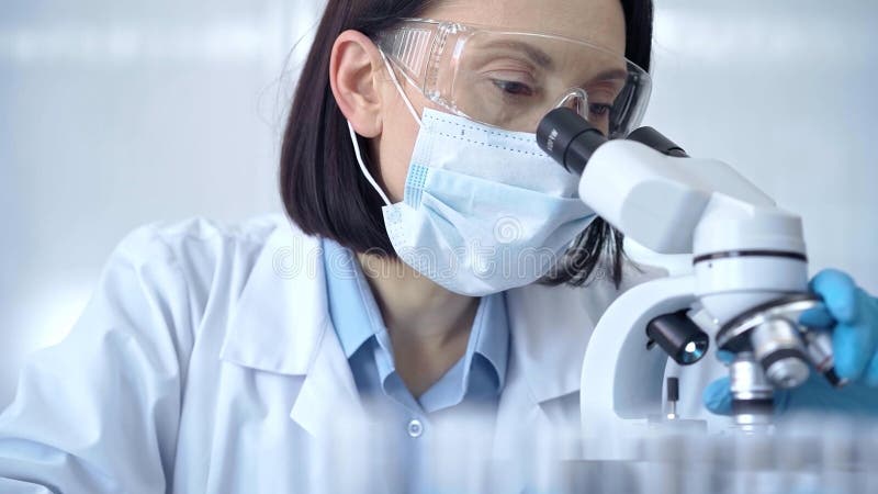 Female Scientist in Lab Goggles, Protective Mask and Gloves is Using ...