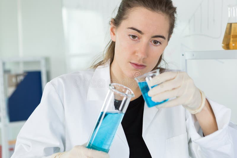 Female Scientist Putting Blue Liquid into Flask Stock Photo - Image of ...