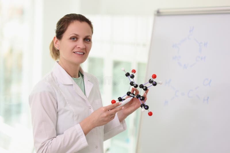 Female Scientist Standing Near Whiteboard, Pointing To Molecular Model ... Female Scientist Standing Near Whiteboard, Pointing To Molecular Model ...