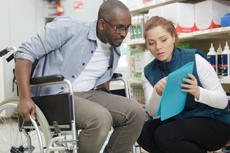 Female Shop Assistant Serving Customer in Wheelchair Stock Image ...