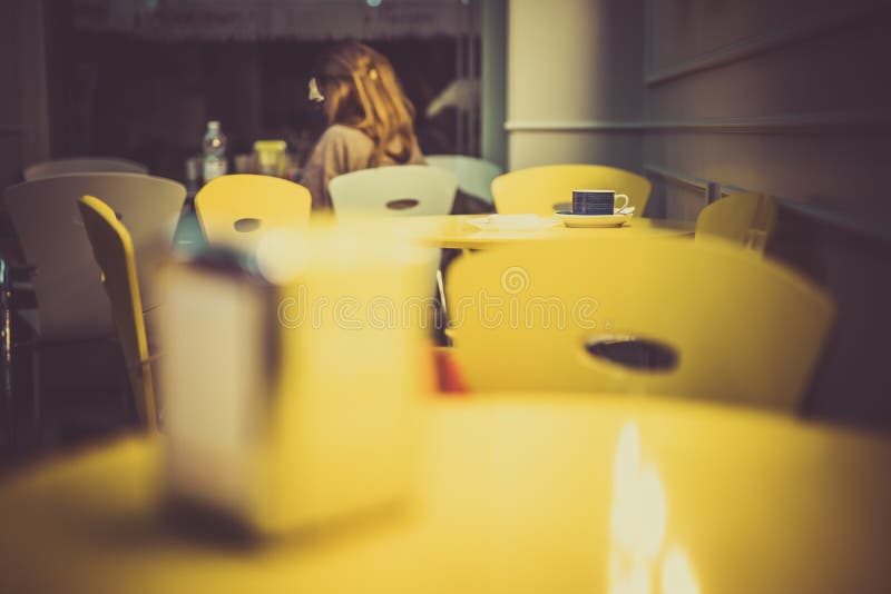 Female Sitting Alone in an Empty Restaurant with Yellow Chairs and ...