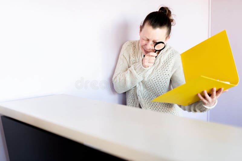Female Sitting at a Countertop, Sorting through a Yellow File Folder ...