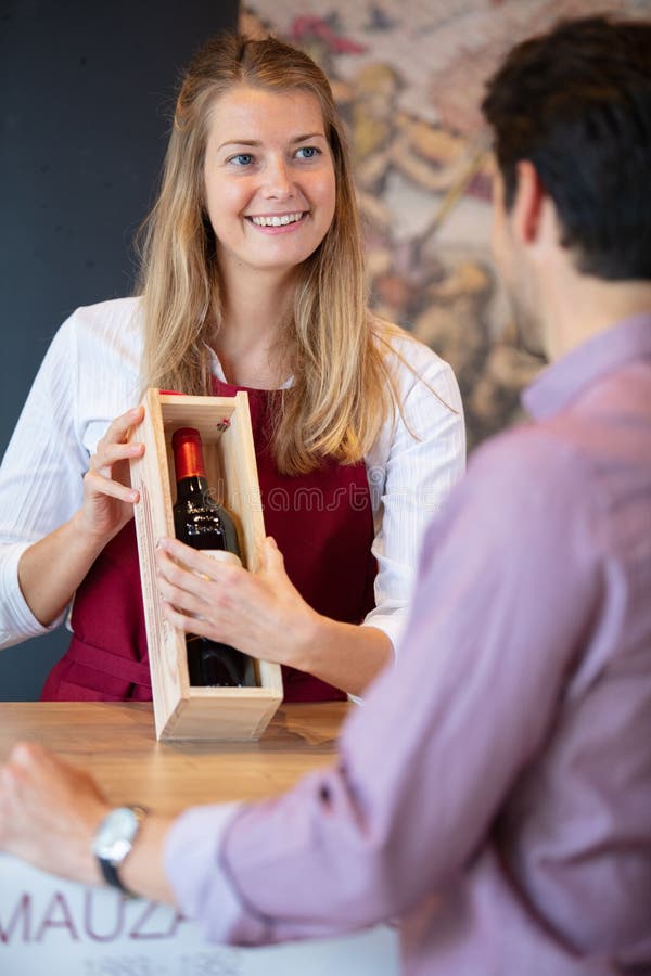 Female Sommelier in Wine Store Giving Customer Wine Stock Photo - Image ...