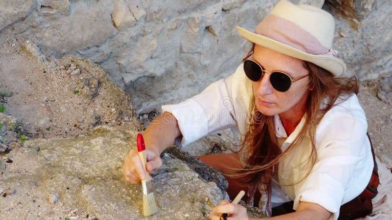 A Female Student Archaeologist at an Excavation Site Cleans the ...