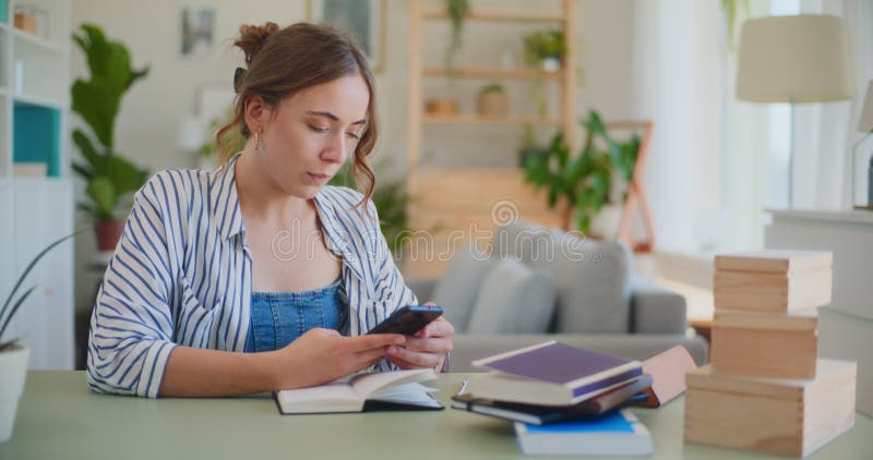 Female Student Browsing Smartphone while Learning at Desk Stock Video ...