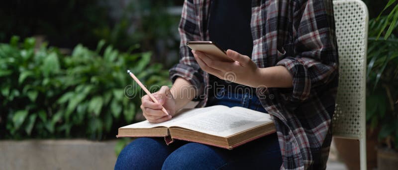 Female Student Reading Book and Using Smartphone in Garden Stock Image ...
