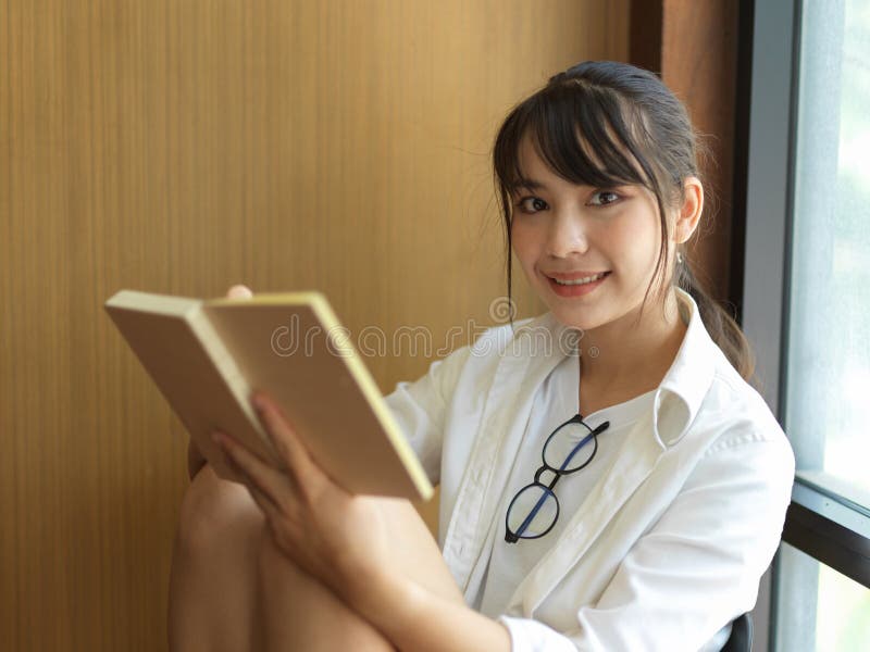Female Student Smiling To Camera while Reading Book in Reading Corner ...