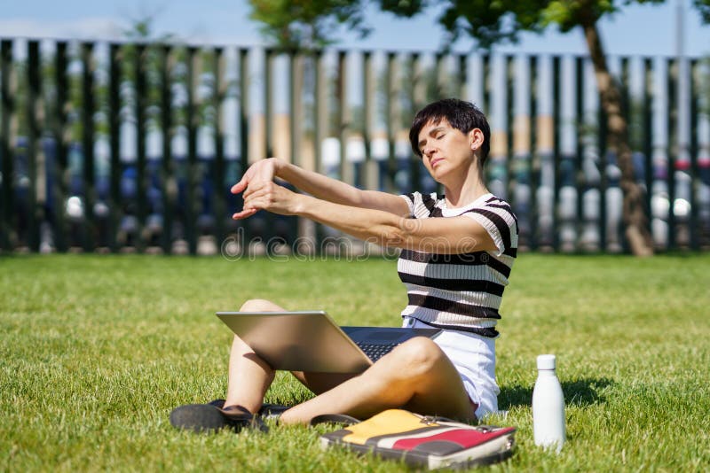 Female Student Stretching on Green Lawn in Park and Laptop with Folder ...