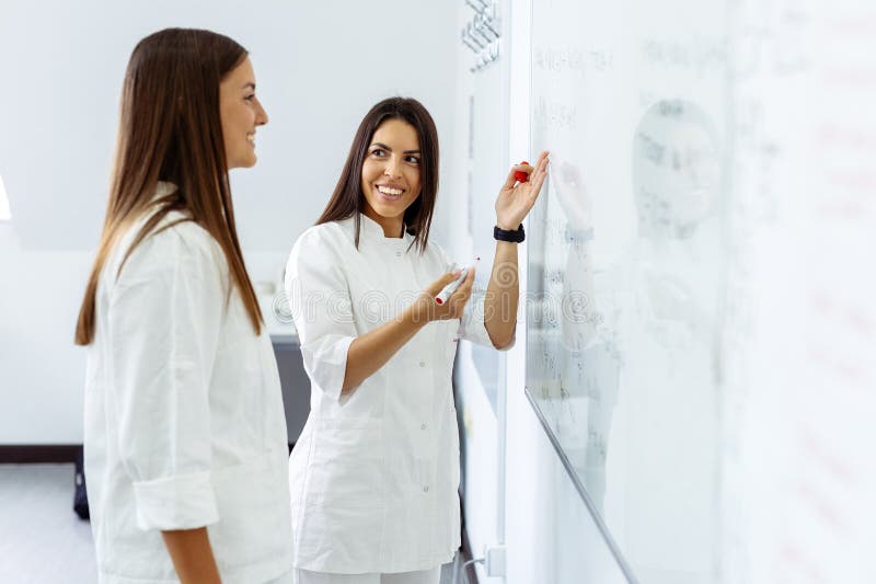 Female Student Writing on Glass Board in Classroom. Stock Photo - Image ...