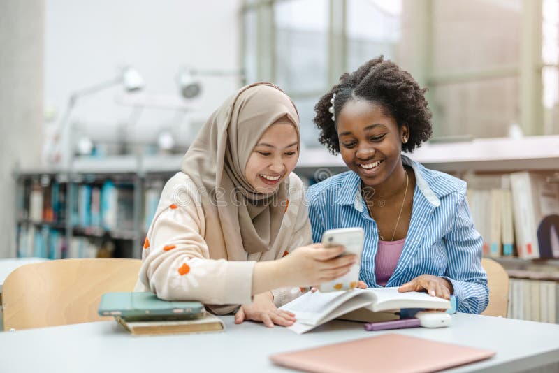 Female Students Using Smartphone while Sitting in a Library Stock Photo ...