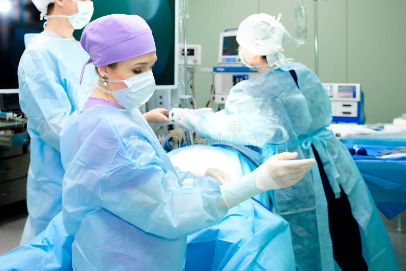Female Surgeon Puts On Sterile Gloves In The Operating Room Stock