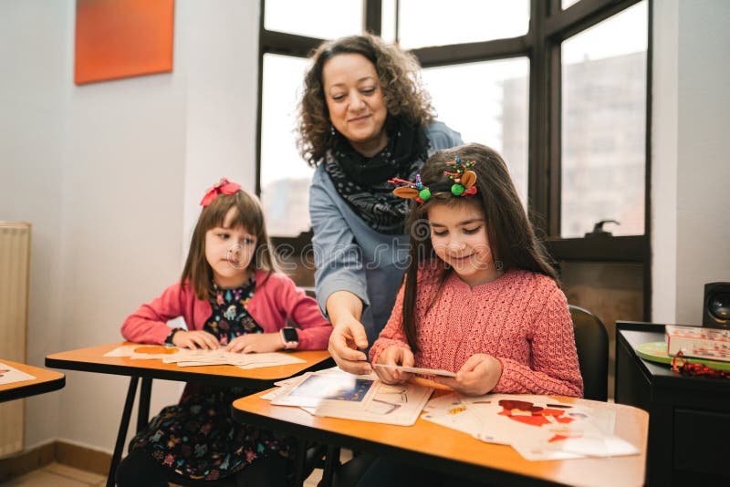 Female Teacher Helping Elementary Students at Language School Class ...
