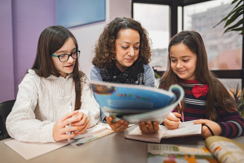 Female Teacher Helping Elementary Students at Language School Class ...