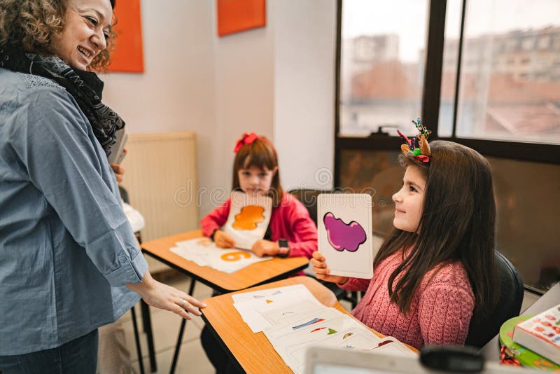 Female Teacher Helping Elementary Students at Language School Class ...