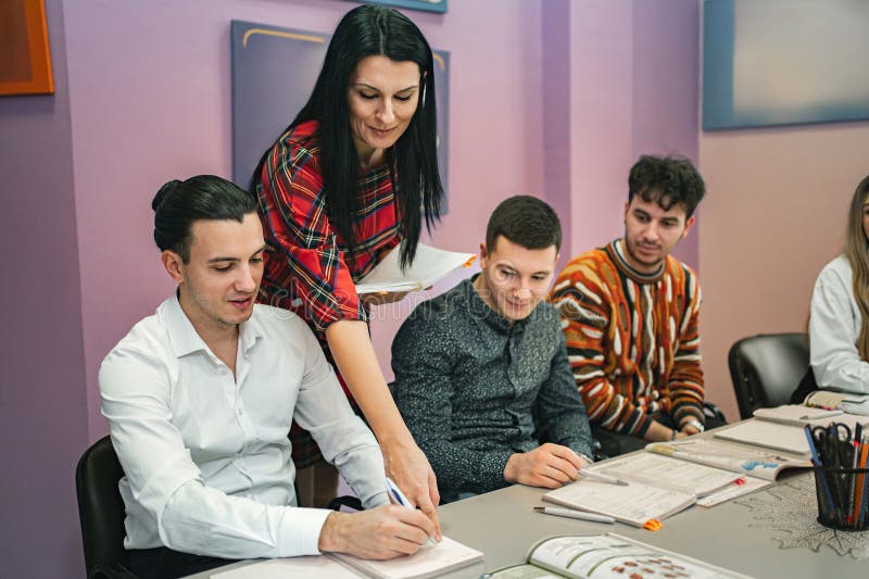 Female Teacher Helping Her Male Students at Language School Stock Image ...