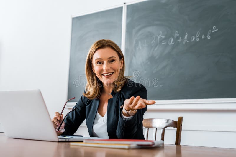 Female Teacher Sitting at Computer Desk, Holding Glasses and Looking at ...