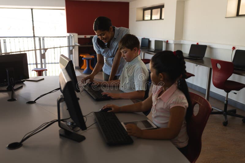 Female Teacher Teaching Computer To Schoolkid at Desk in School Stock ...