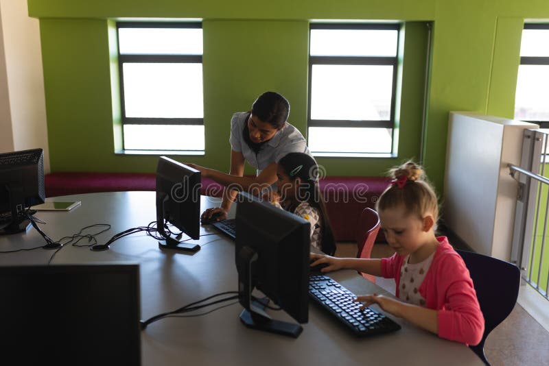 Female Teacher Teaching Computer To Schoolkid at Desk in School Stock ...
