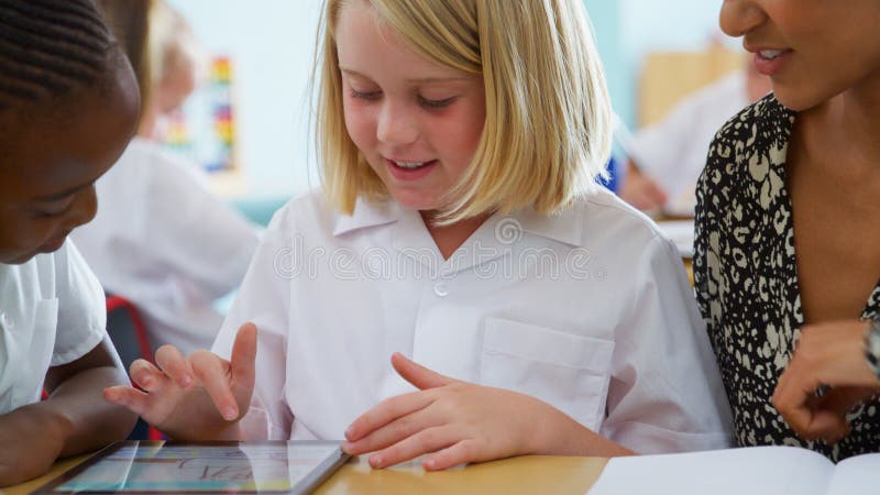 Female Teacher with Two Elementary School Pupils Wearing Uniform Using ...