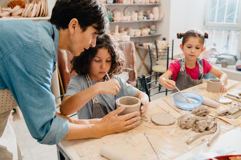 Female Teacher Making Pottery Crafts with Group of Kids at Workshop ...