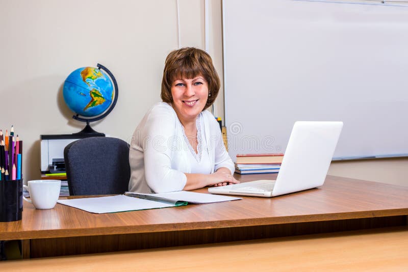 A Female Teacher Works at a Computer in the Classroom Stock Image ...