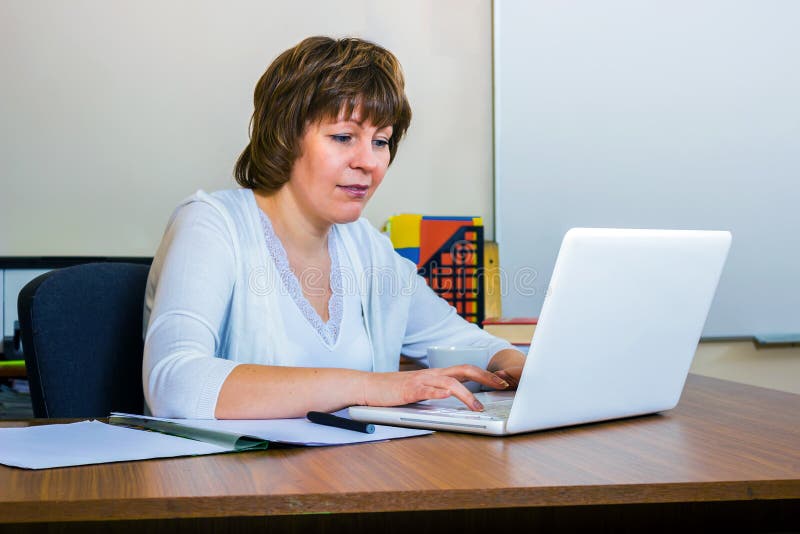 A Female Teacher Works with a Laptop in the Classroom Stock Photo ...