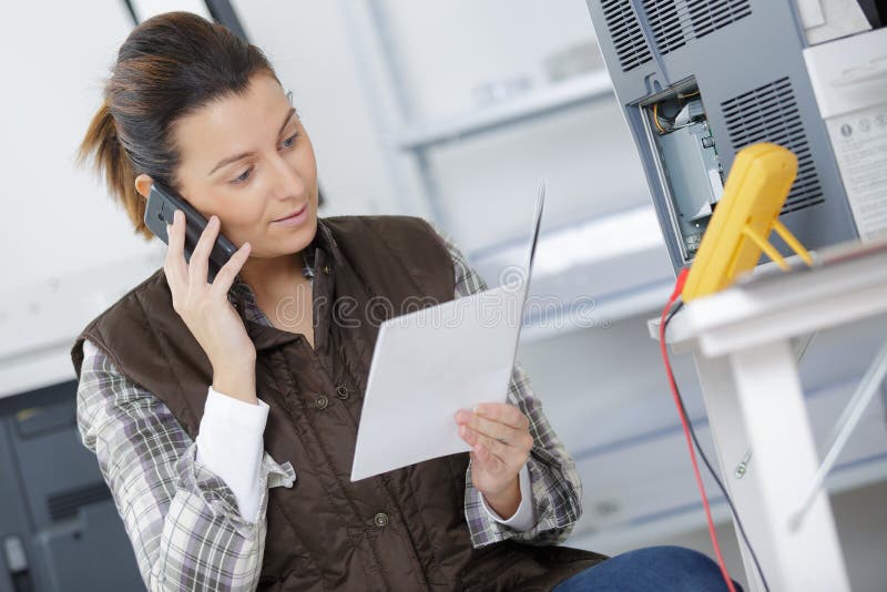 Female Technician Reading Manual and Speaking on Phone Stock Photo ...