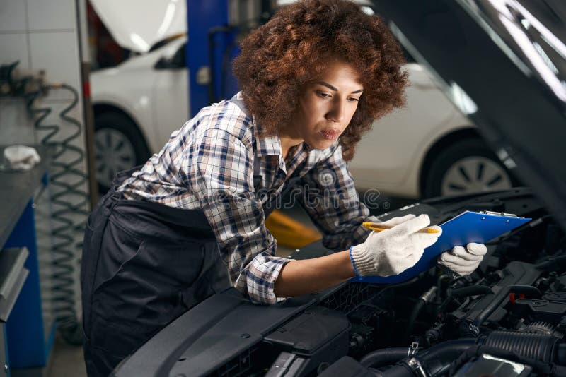 Female Technician in Work Clothes Stands Near Car with Open Hood Stock ...