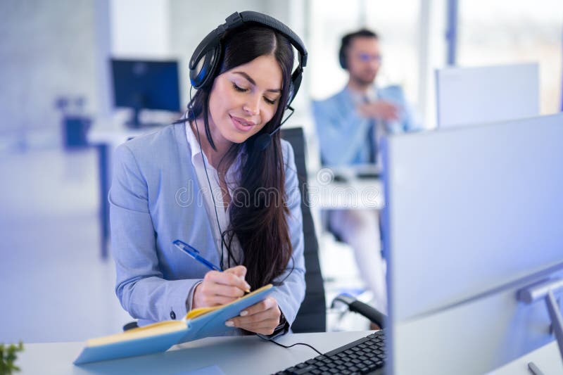 Female Telephone Operator Wearing Headset Taking Notes, Communicating ...