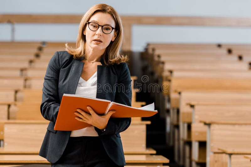 Female University Professor Looking at Camera, Holding Journal and ...