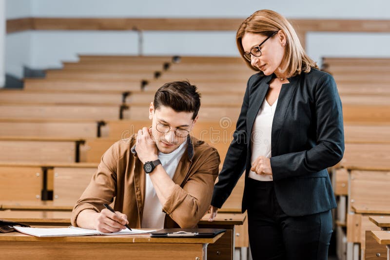 Female University Teacher Looking at Male Student Writing Exam Stock ...