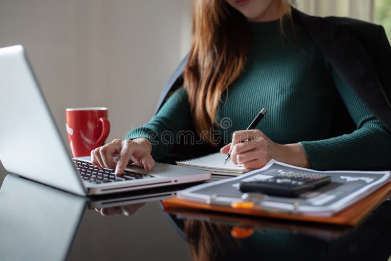 Female Use a Laptop Computer and Take Notes in the Notebook at the ...