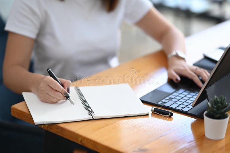 A Female Using Computer Tablet and Making Notes or Planning Schedule in ...