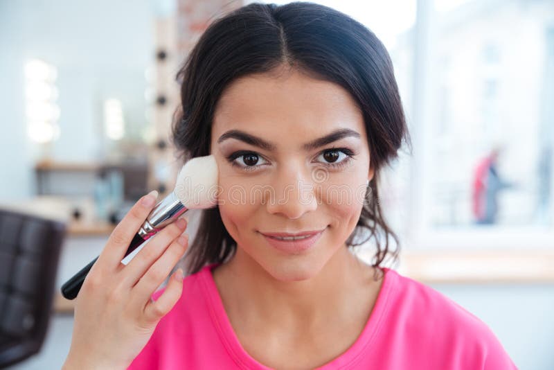 Female Visagist With Brush Doing Professional Makeup To Smiling Woman
