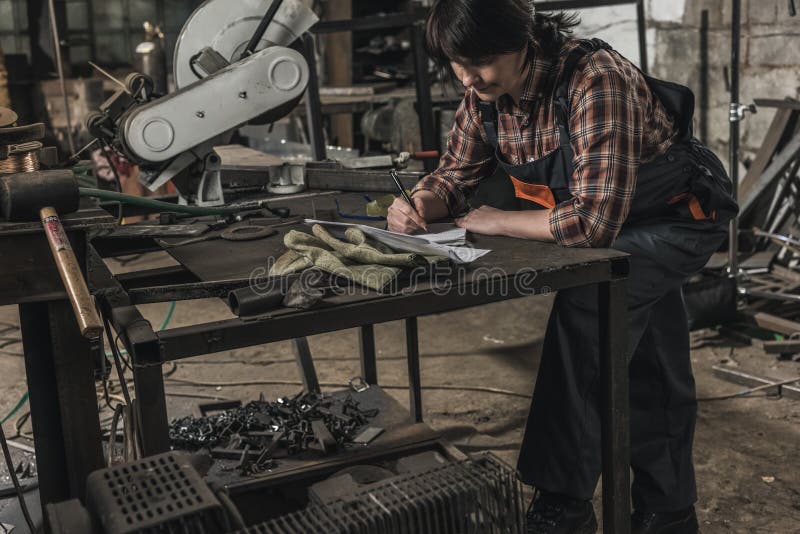 Female Welder Doing Paperwork at Table Stock Photo - Image of ...