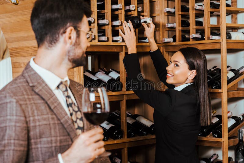 Female Wine Steward Taking Bottle from Shelf for Client Stock Image ...