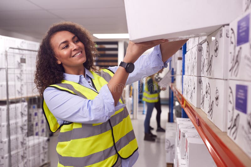 Female Worker Inside Busy Warehouse Putting Box Onto Shelf Stock Photo ...