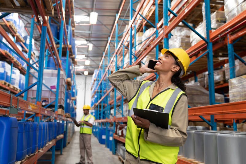 Female Worker Looking Up while Talking on Mobile Phone in Warehouse ...